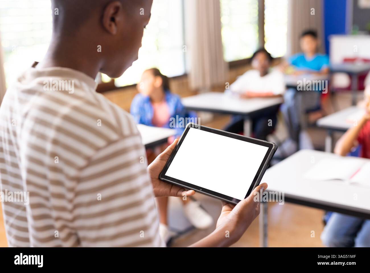 Holding tablet, student presenting to classmates in school classroom ...