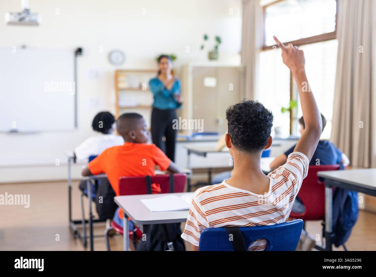 In school, student raising hand to ask question in classroom with ...