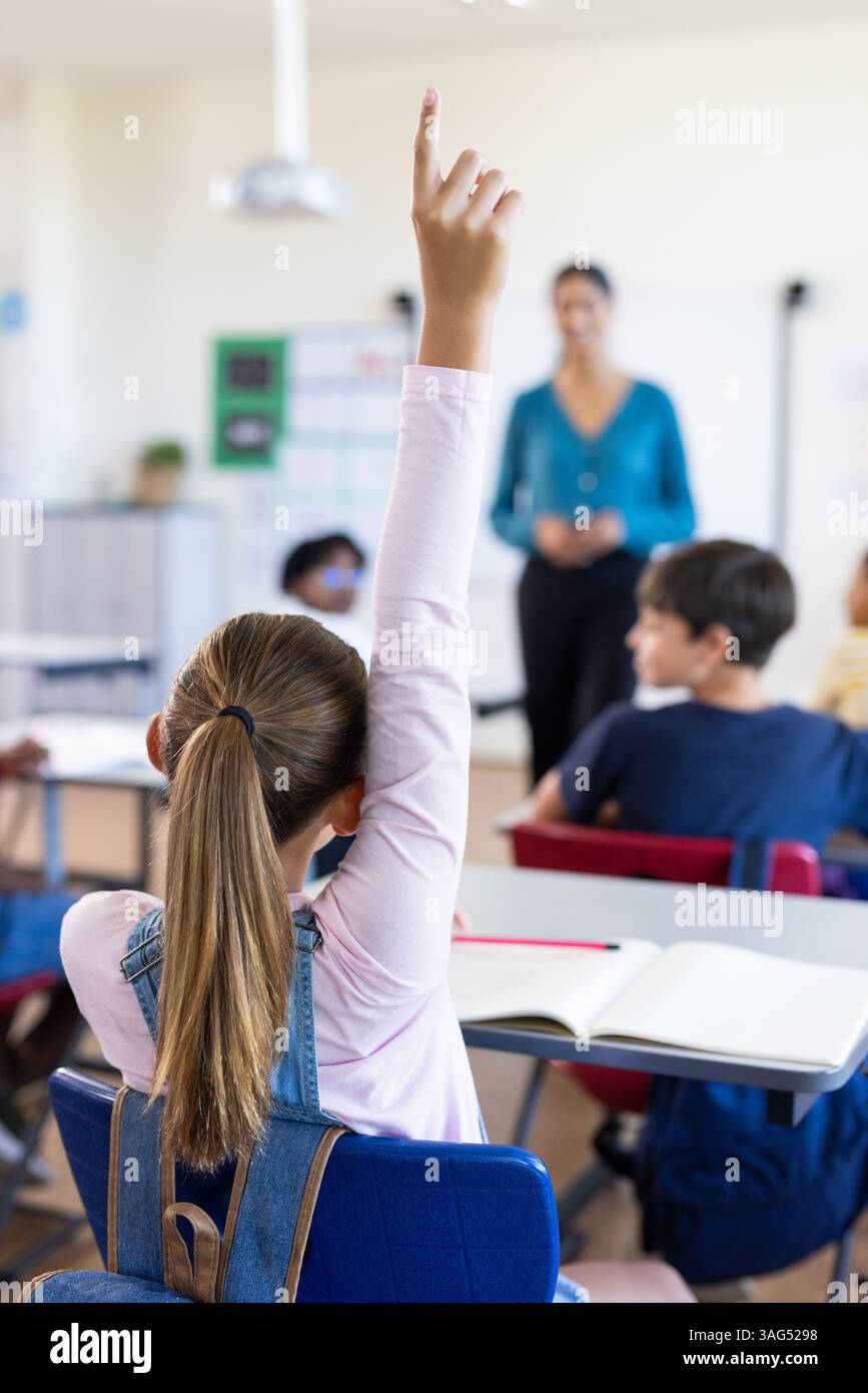 In school, girl raising hand to ask question in classroom with Indian ...