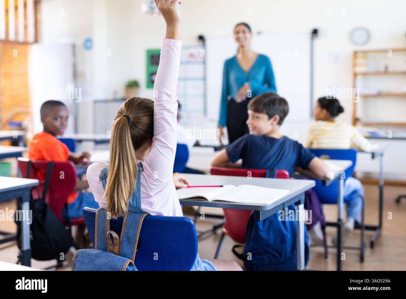 In school, student raising hand to answer question in classroom with ...