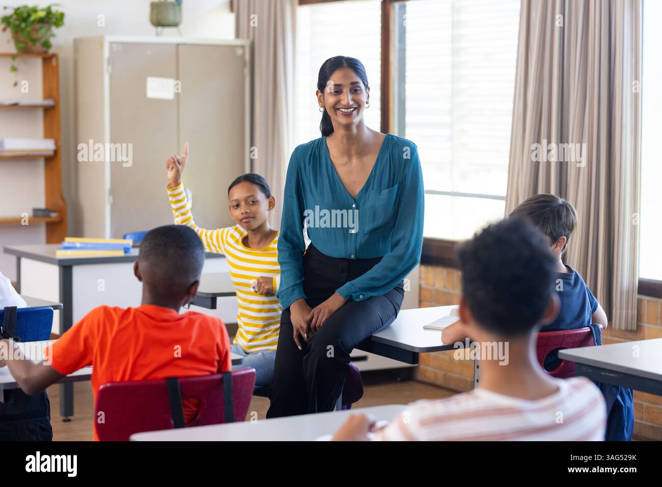 In school, Indian female teacher smiling while students participating ...
