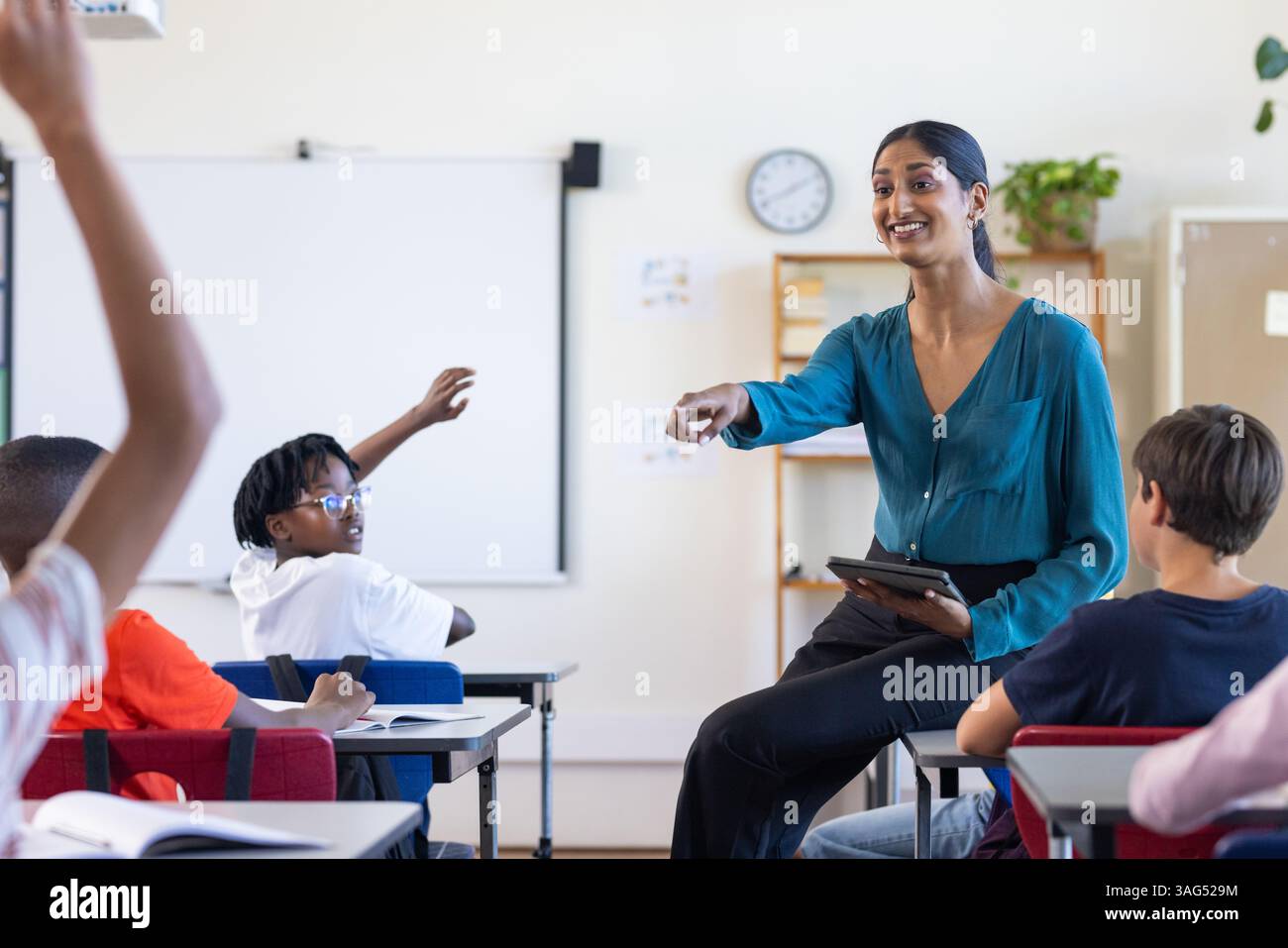 In school, Indian female teacher holding tablet and engaging with ...