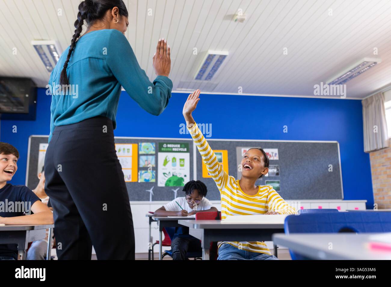 In school, Indian female teacher giving high-five to excited student in ...
