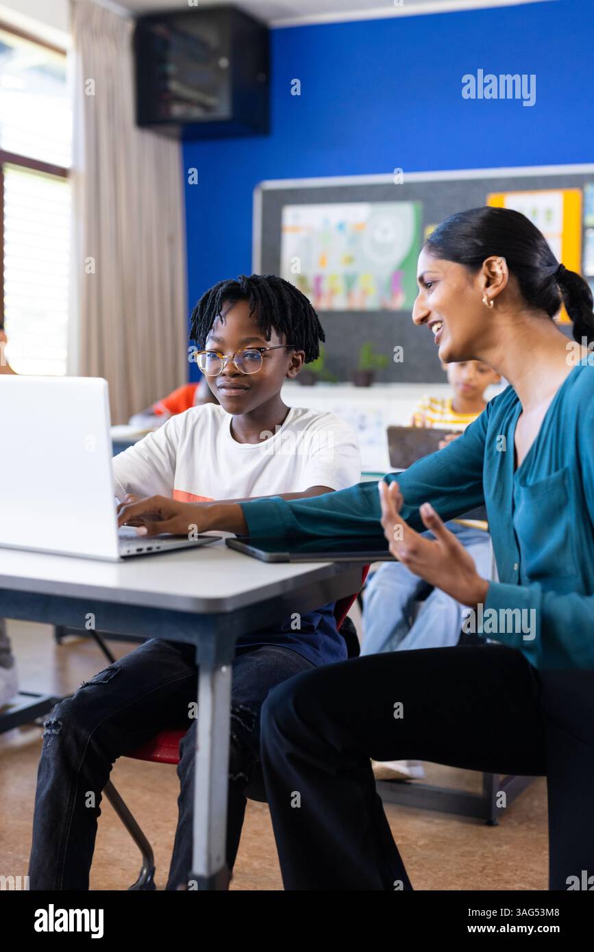 In school, Indian female teacher helping student with laptop in ...