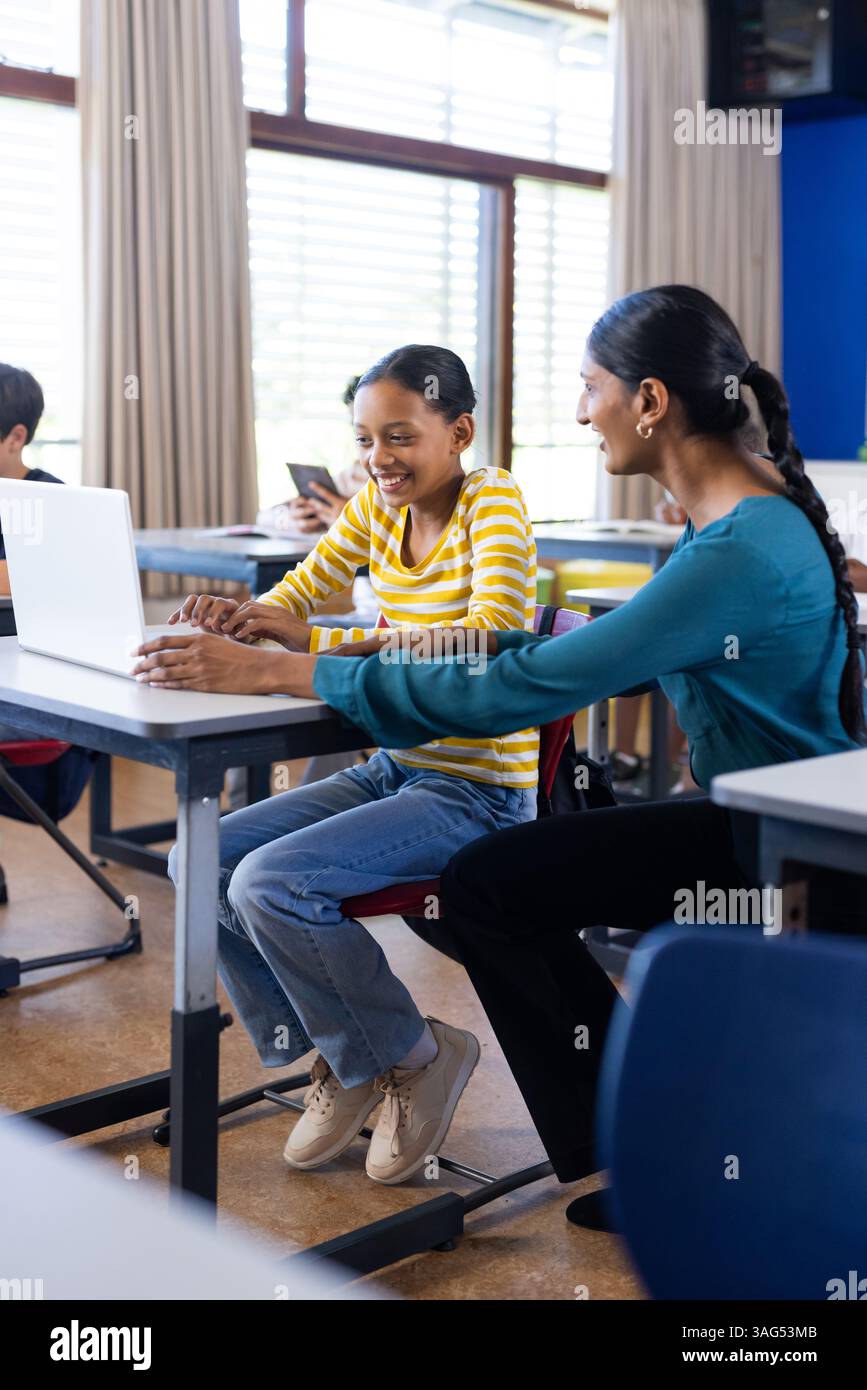 In school, Indian female teacher helping student using laptop in ...