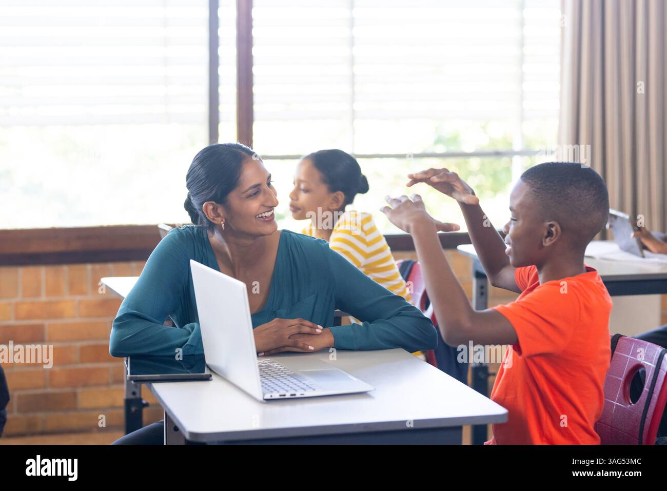 In school, Indian female teacher with laptop engaging with students in ...