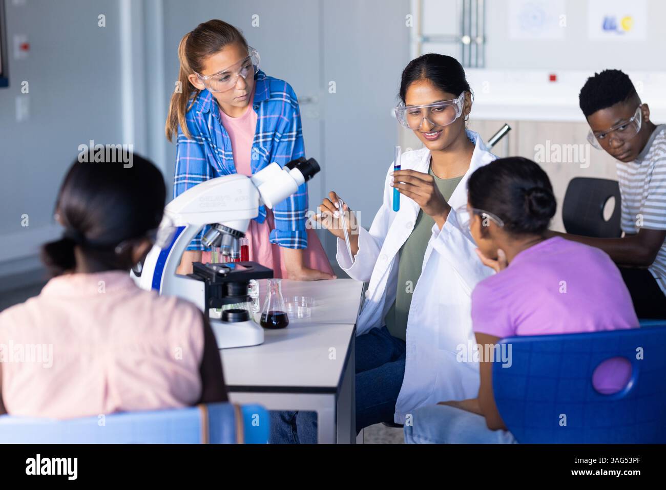 Indian female teacher demonstrating experiment with microscope and test ...