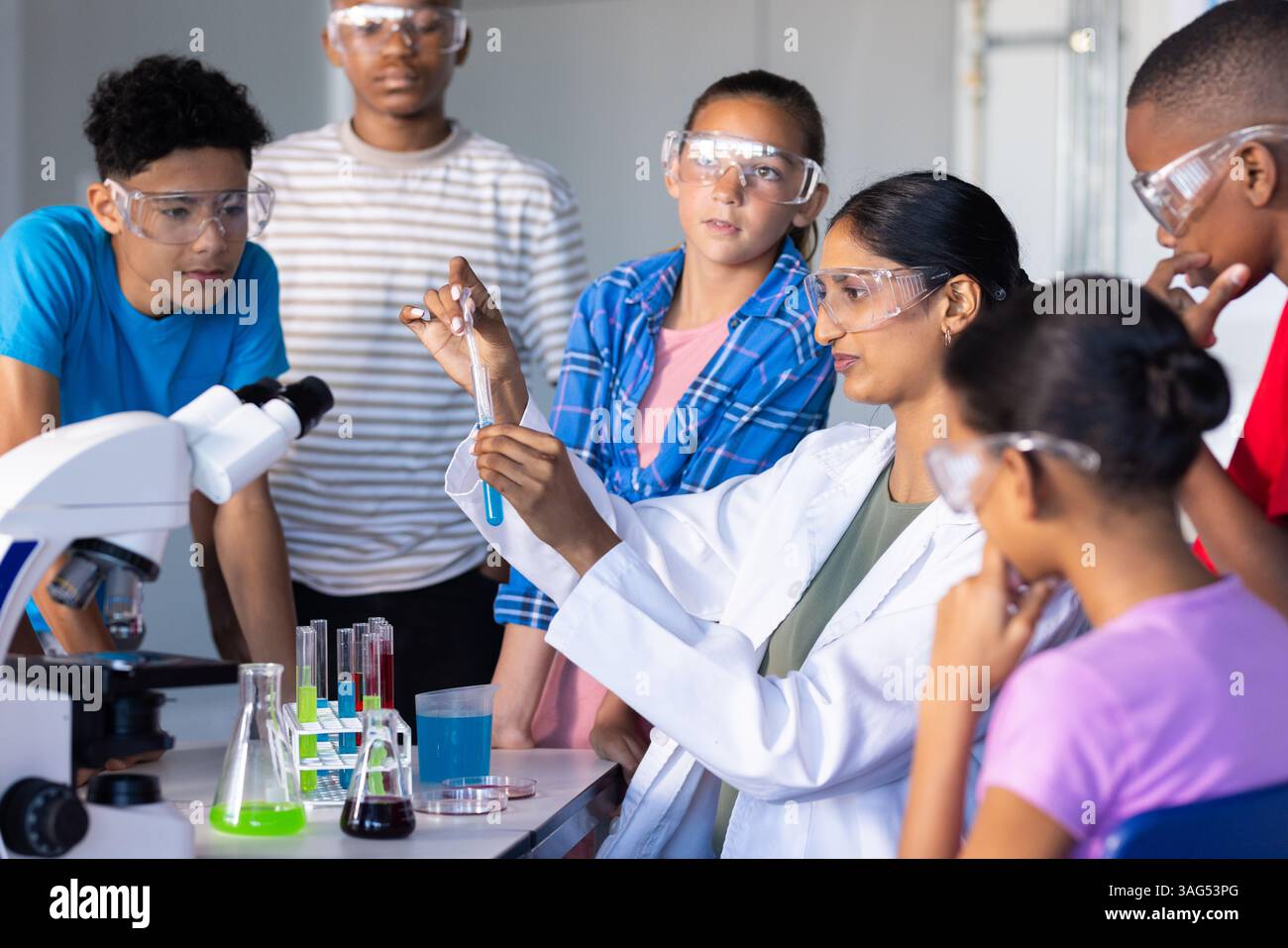 In school, Indian female teacher showing test tube experiment to ...