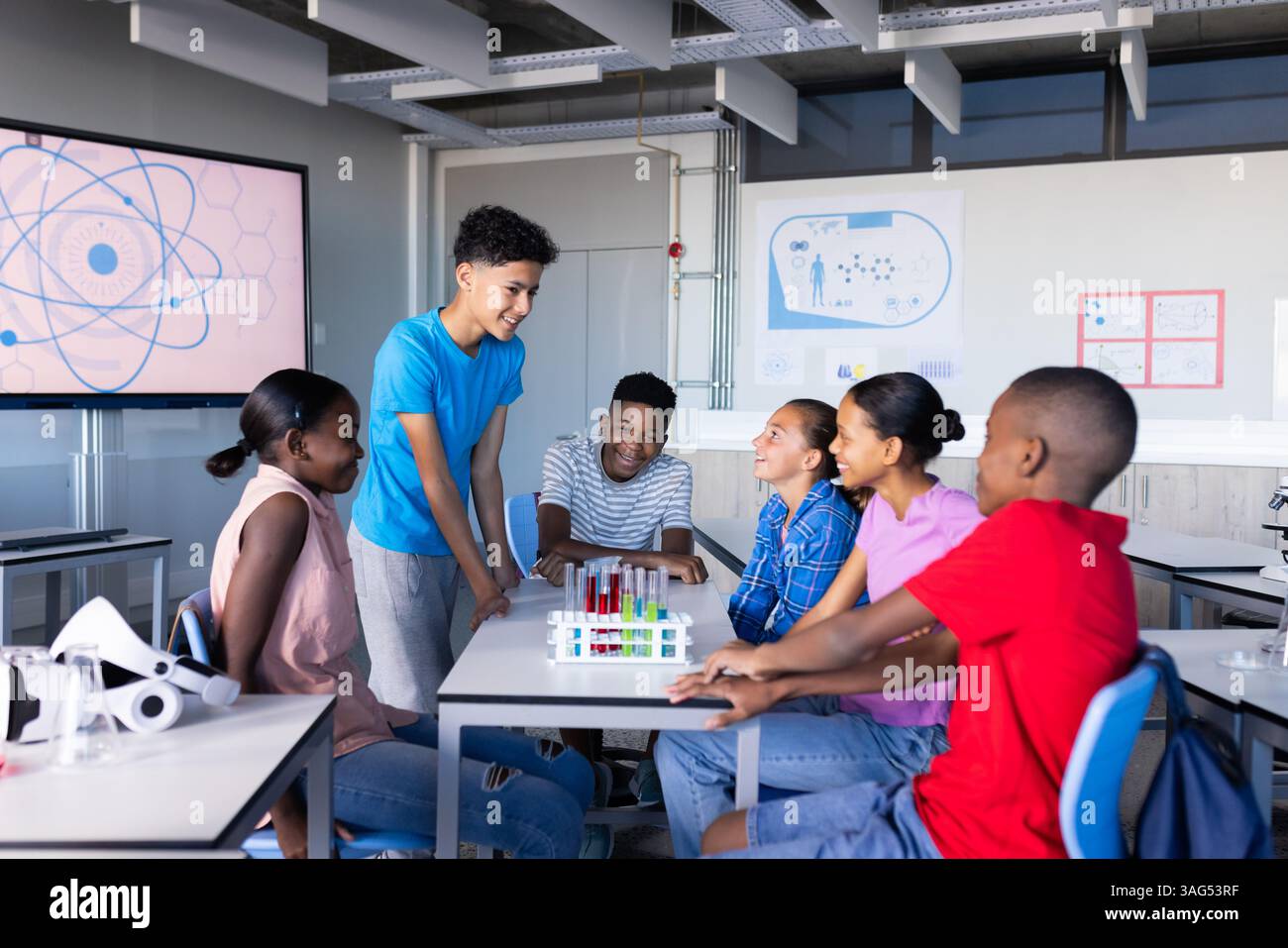 In school, group of students discussing science project with test tubes ...