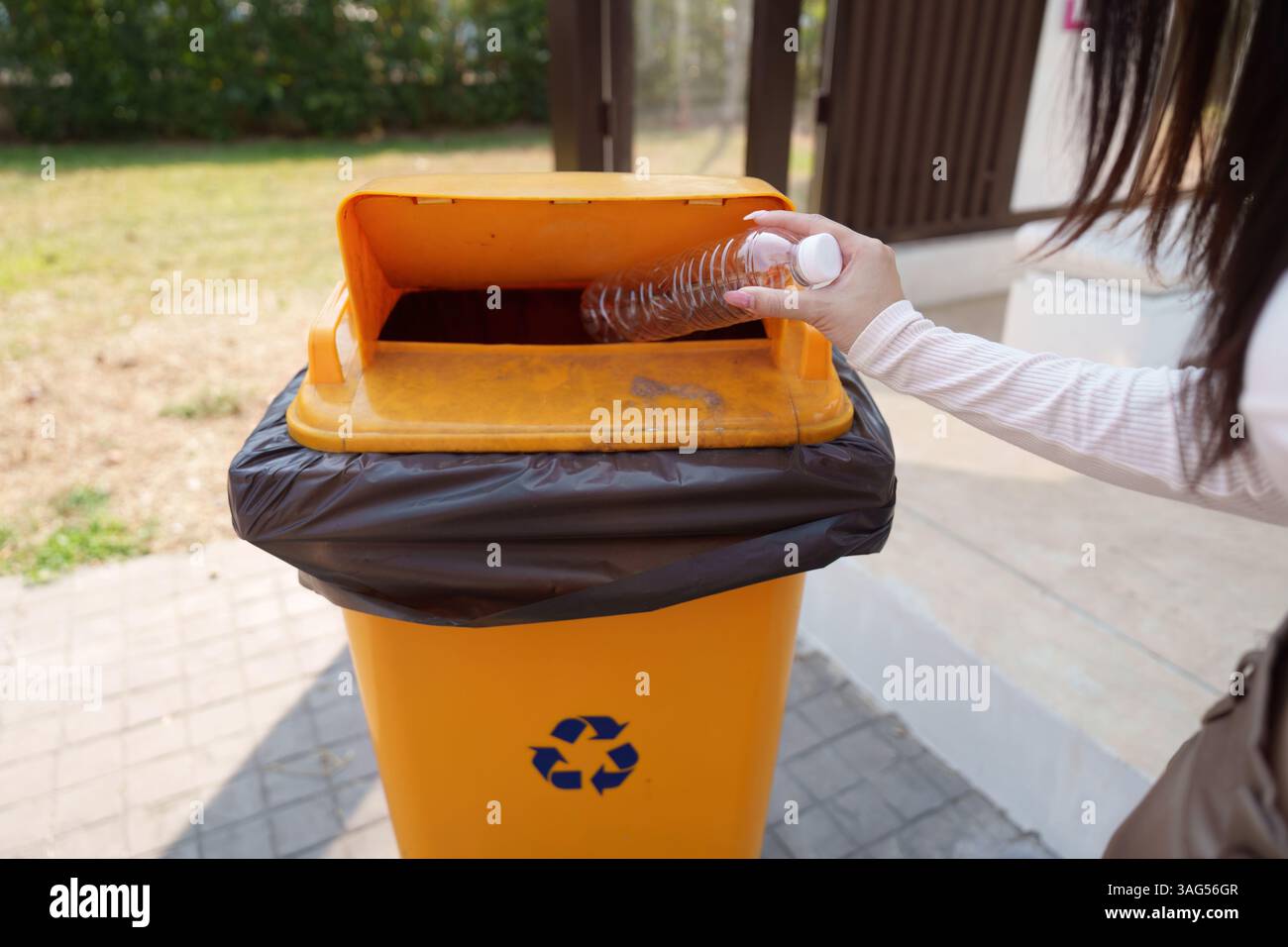 Recycling and Waste Disposal Practices. A woman recycling plastic ...