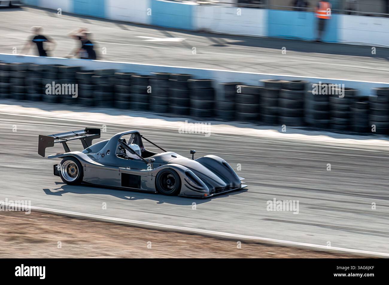 Sleek gray sportscar speeding around racetrack, blurred background ...