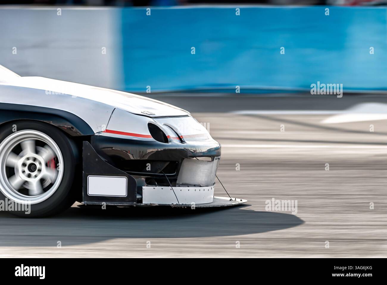 White sports car drifting at high speed on a racetrack, leaving behind ...