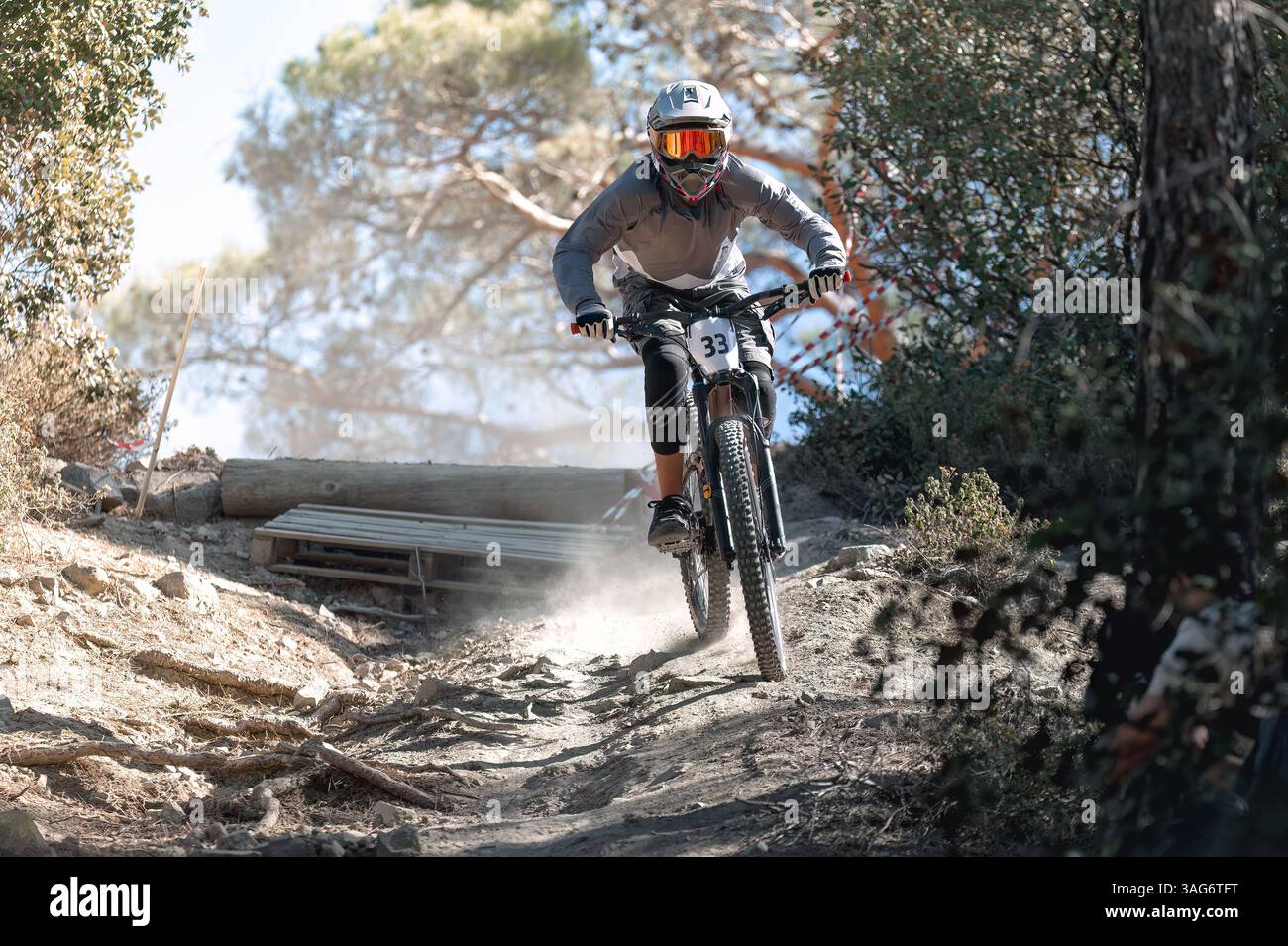 Mountain biker racing downhill on a dusty trail, sending up a dramatic ...