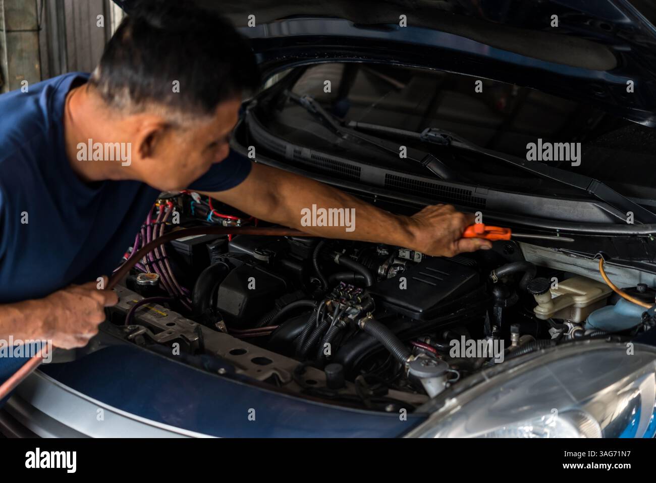 Car mechanic or serviceman cleaning the car engine after checking a car ...