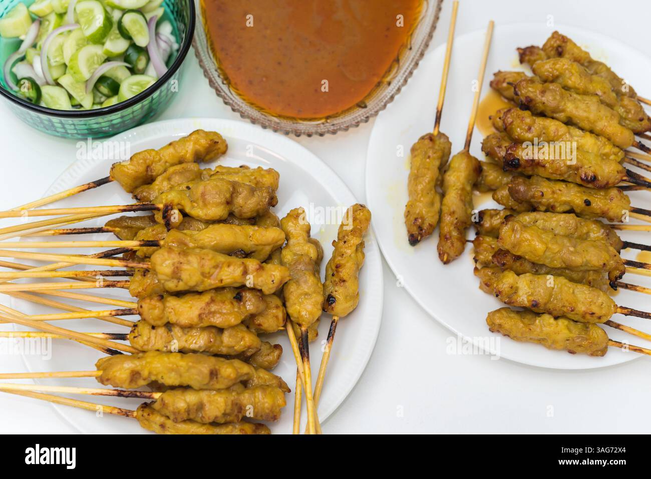 Pork satay with peanut sauce served with pickles which are cucumber ...