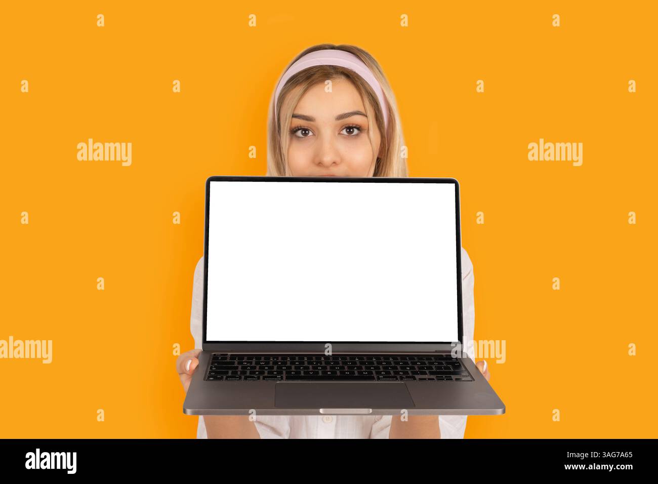 portrait of blonde woman holding laptop. Covering half of face. Empty ...