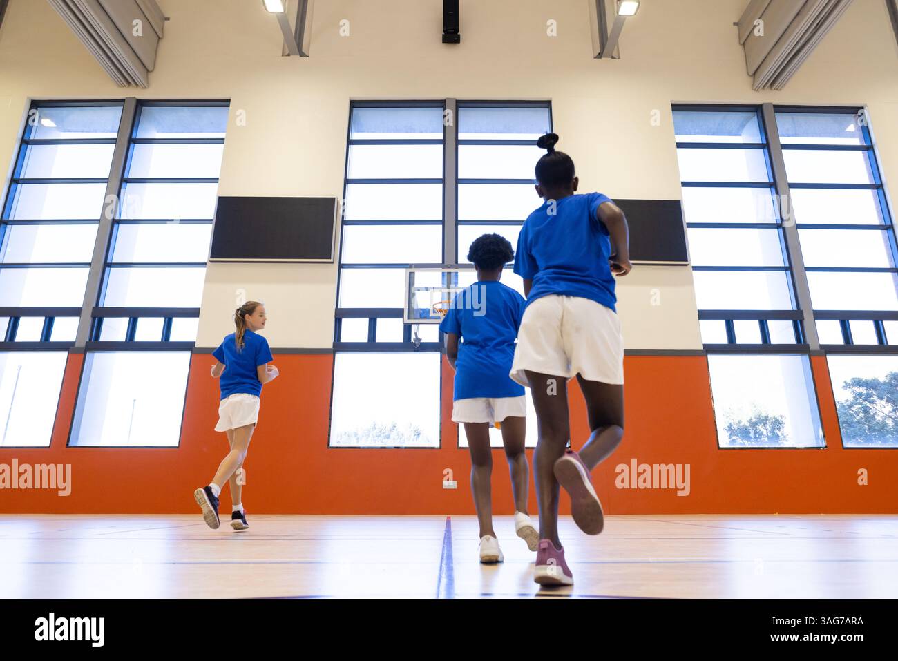 Playing basketball in school gym, diverse girls running towards hoop in ...