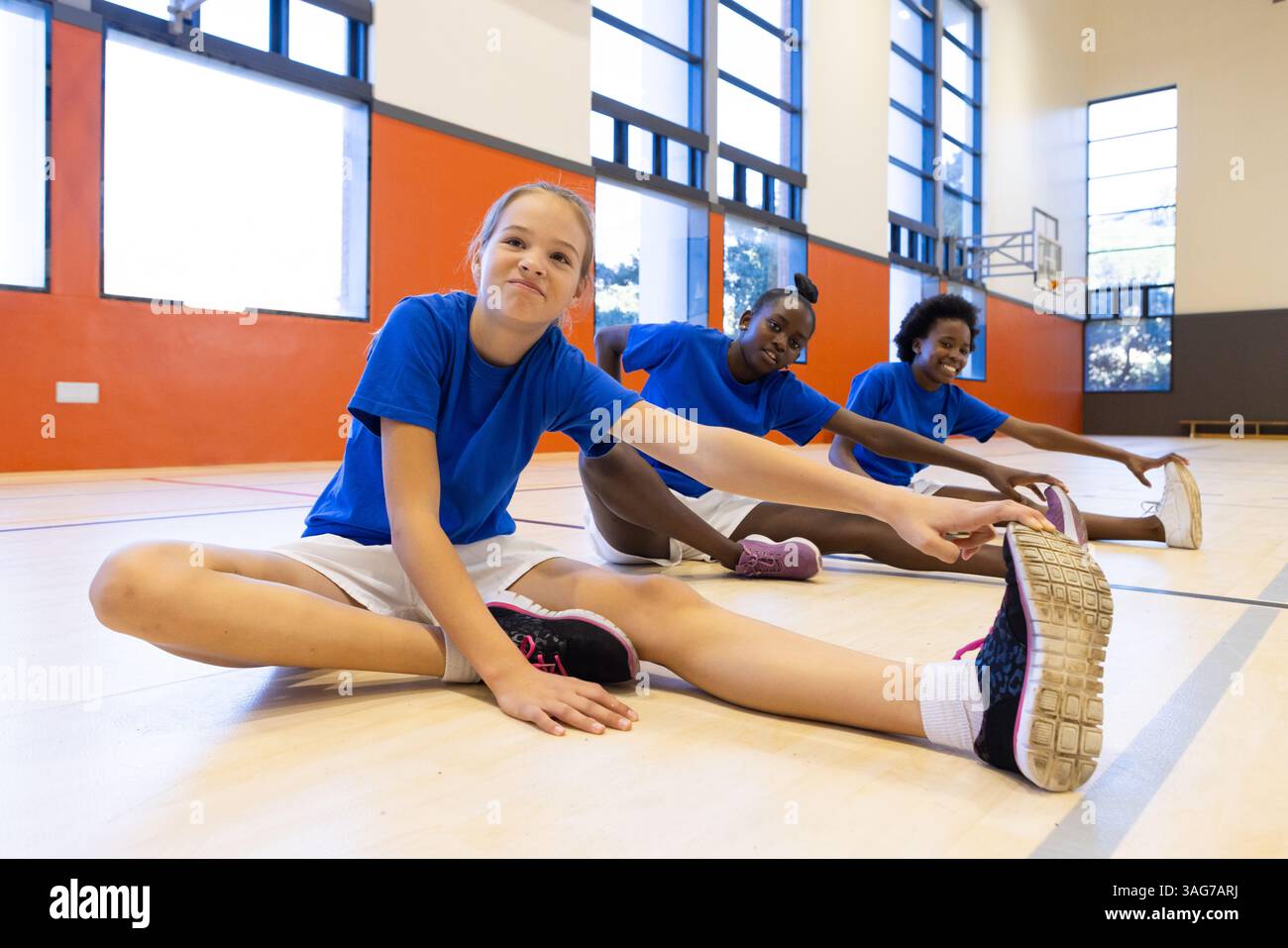 Stretching in gym, three school diverse girls in sports uniforms ...