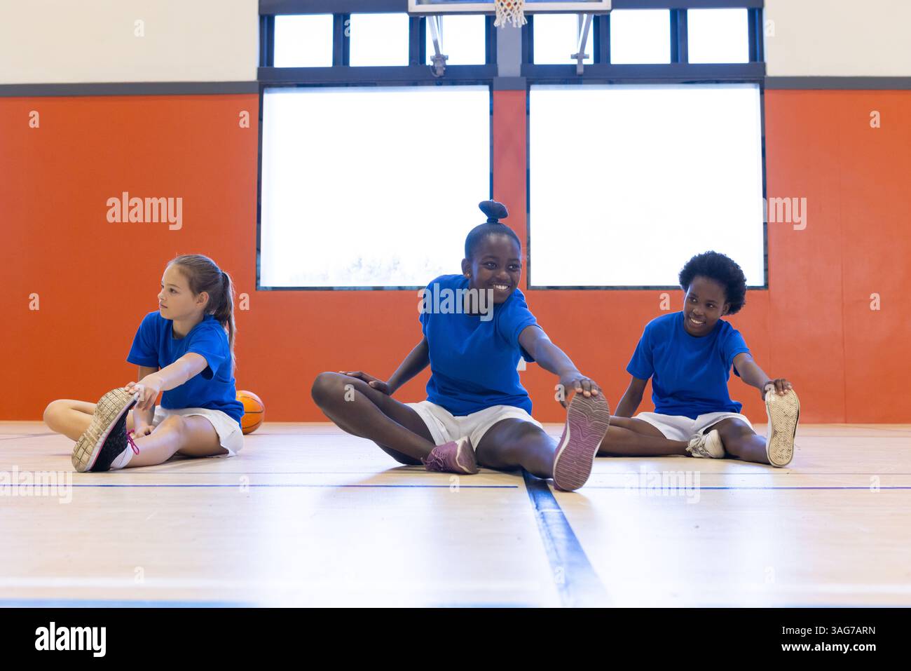 In school gym, diverse girls participating in physical education class ...