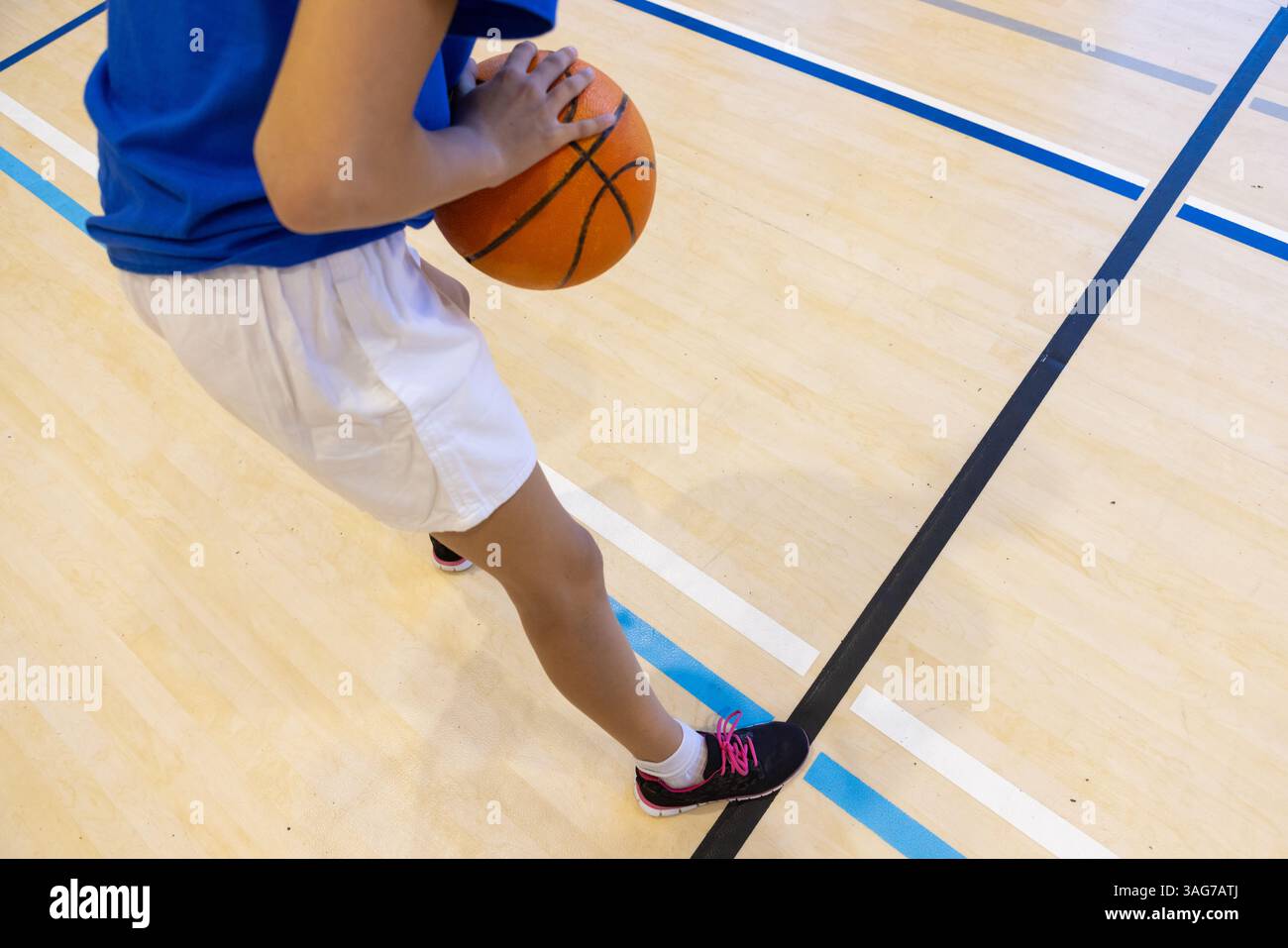Playing basketball in school gym, girl dribbling ball on court Stock ...