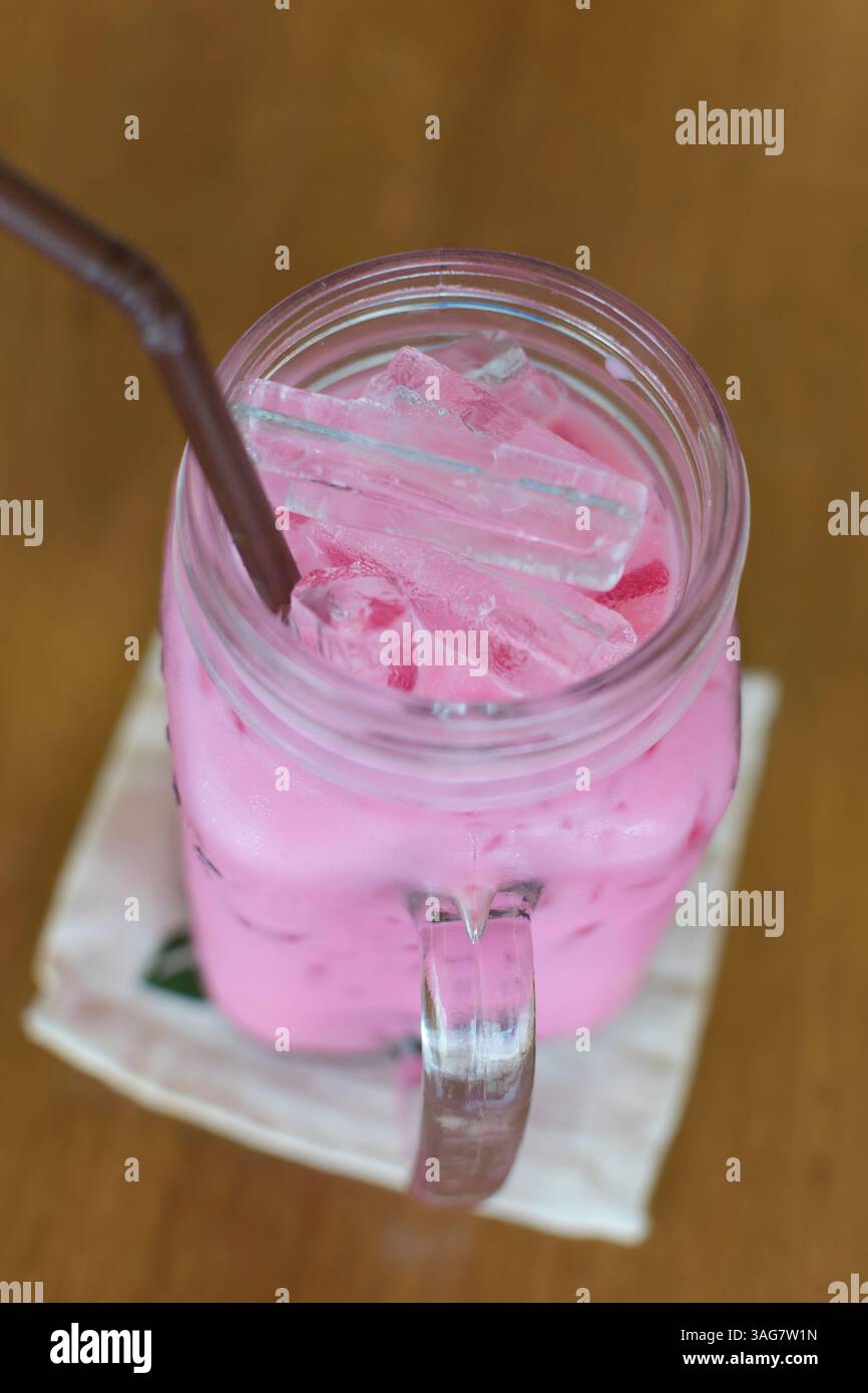 Milk pink sweet cold drink in glass on a wood table Stock Photo - Alamy