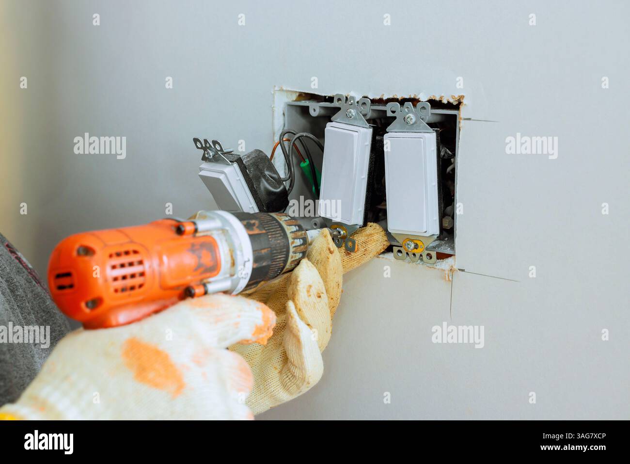 Contractor uses drill to install electrical socket in residential wall ...