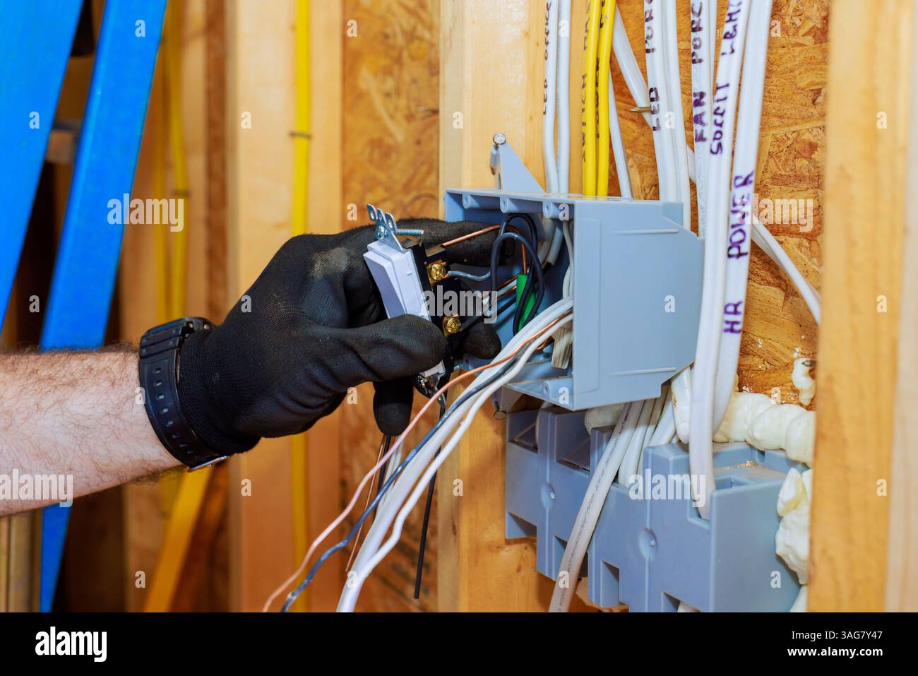 An electrician connects wires to switch in junction box in home being ...