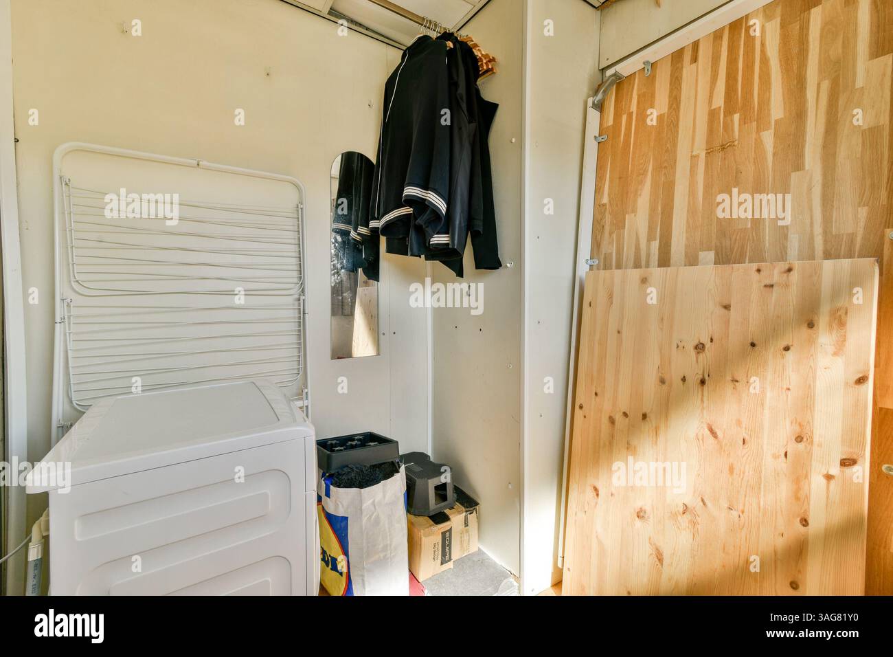 A neatly organized laundry space featuring a drying rack with clothes ...