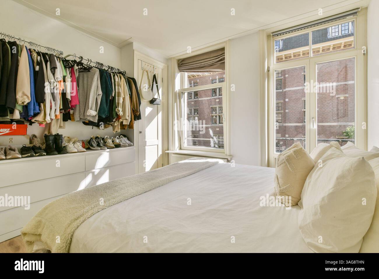 A bright bedroom featuring a neatly organized wardrobe filled with ...