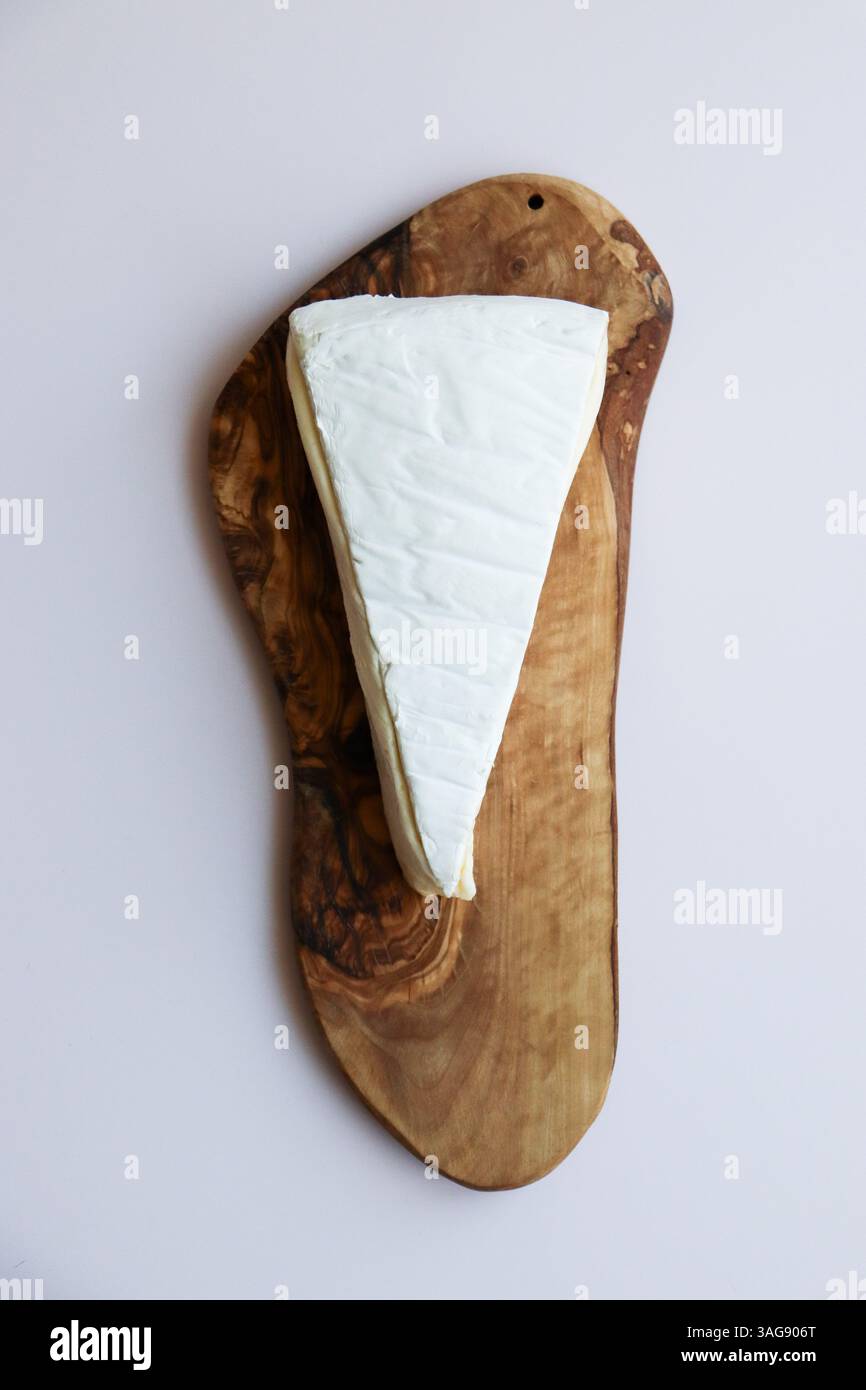 Wedge of brie cheese on a rustic wooden board, platter on a neutral ...