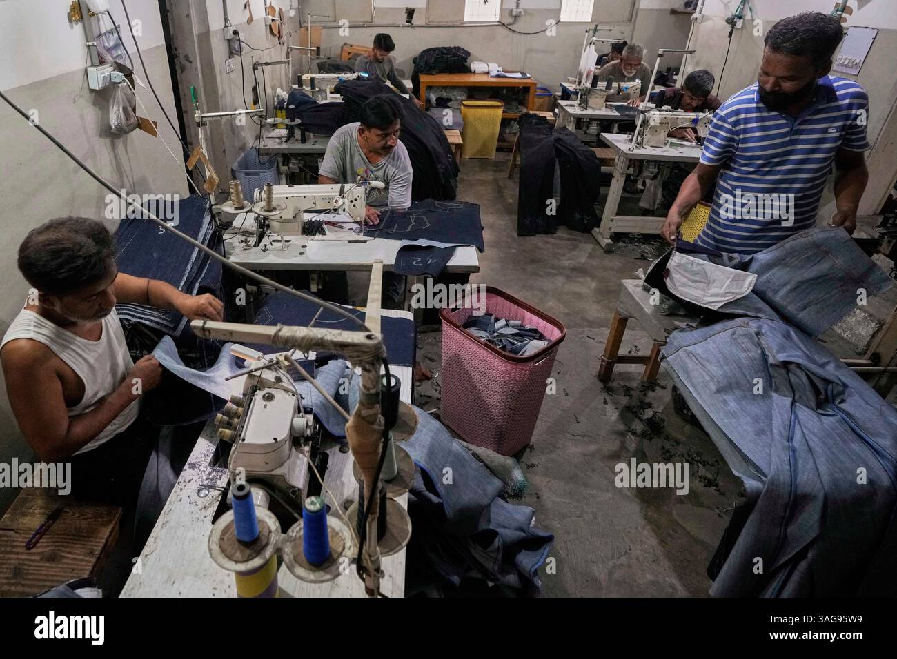 Tailors stitch jeans pants at a small garment factory in Karachi ...