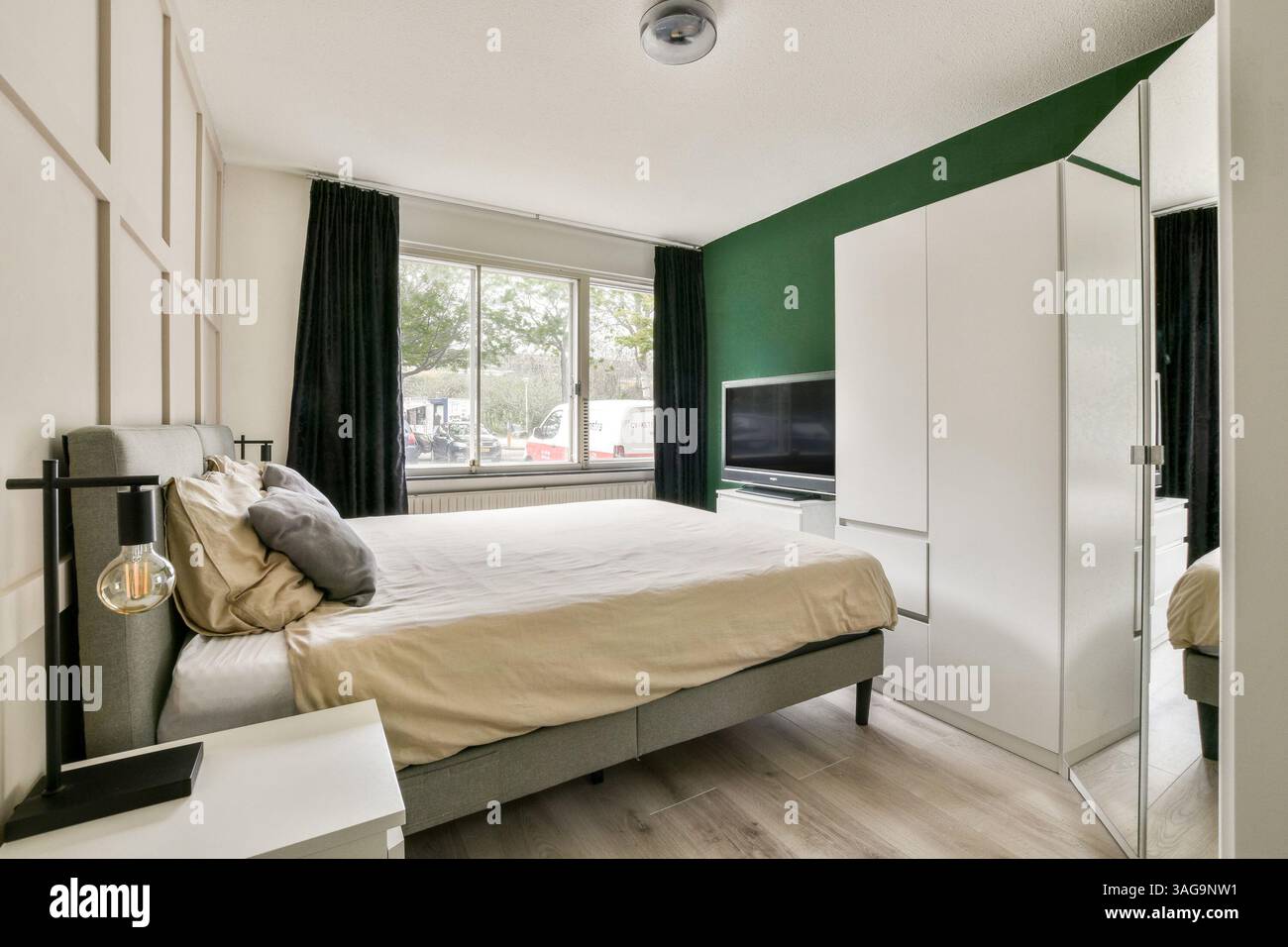 This serene bedroom features a stylish green accent wall, large window ...