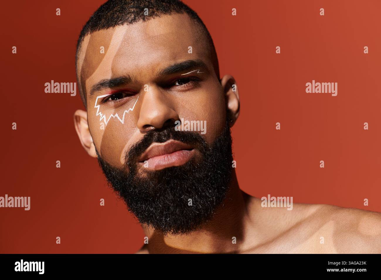 Handsome young man confidently posing with a striking facial design and ...