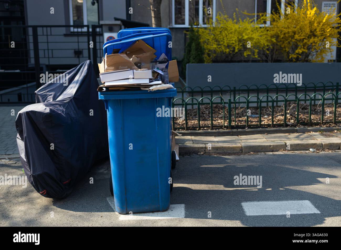 Blue trash bin labeled "PAPIER" for paper waste, overflowing with ...
