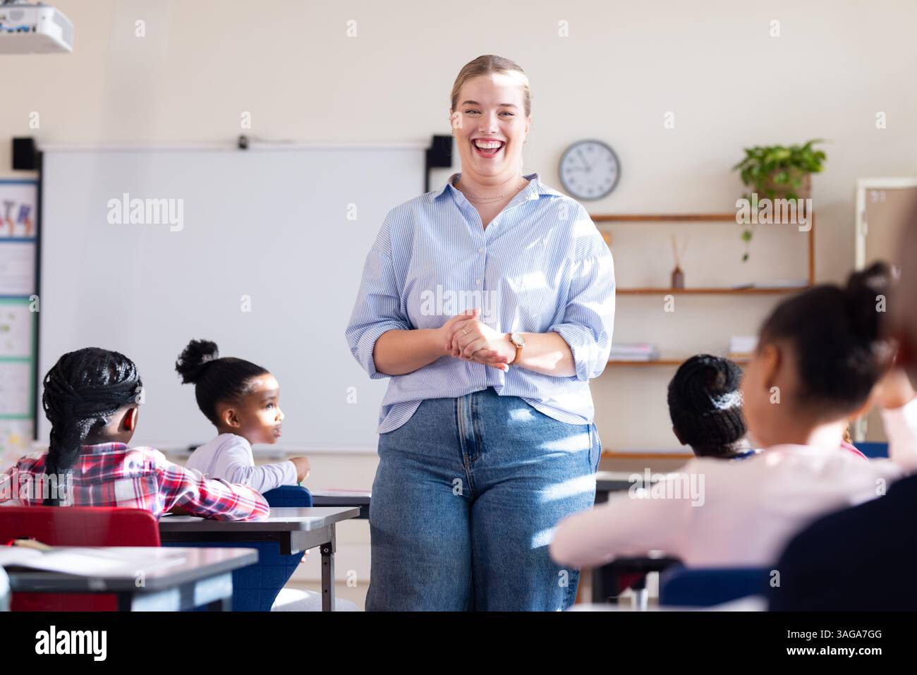 Smiling female teacher engaging with diverse students in classroom ...