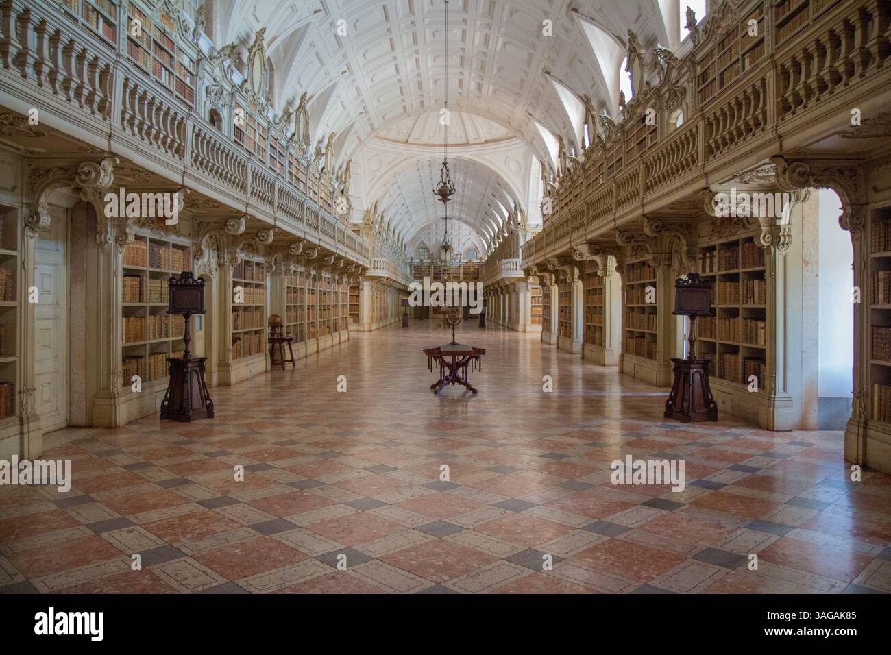 Baroque-style library interior with high vaulted ceiling, ornate bookshelves, and antique globes ...