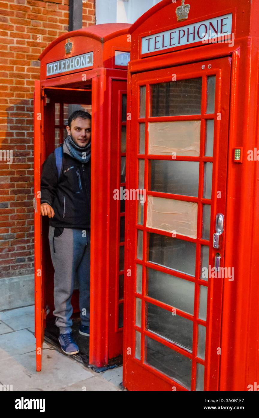 Portrait of a man inside a traditional red phone booth in Guildford, UK ...