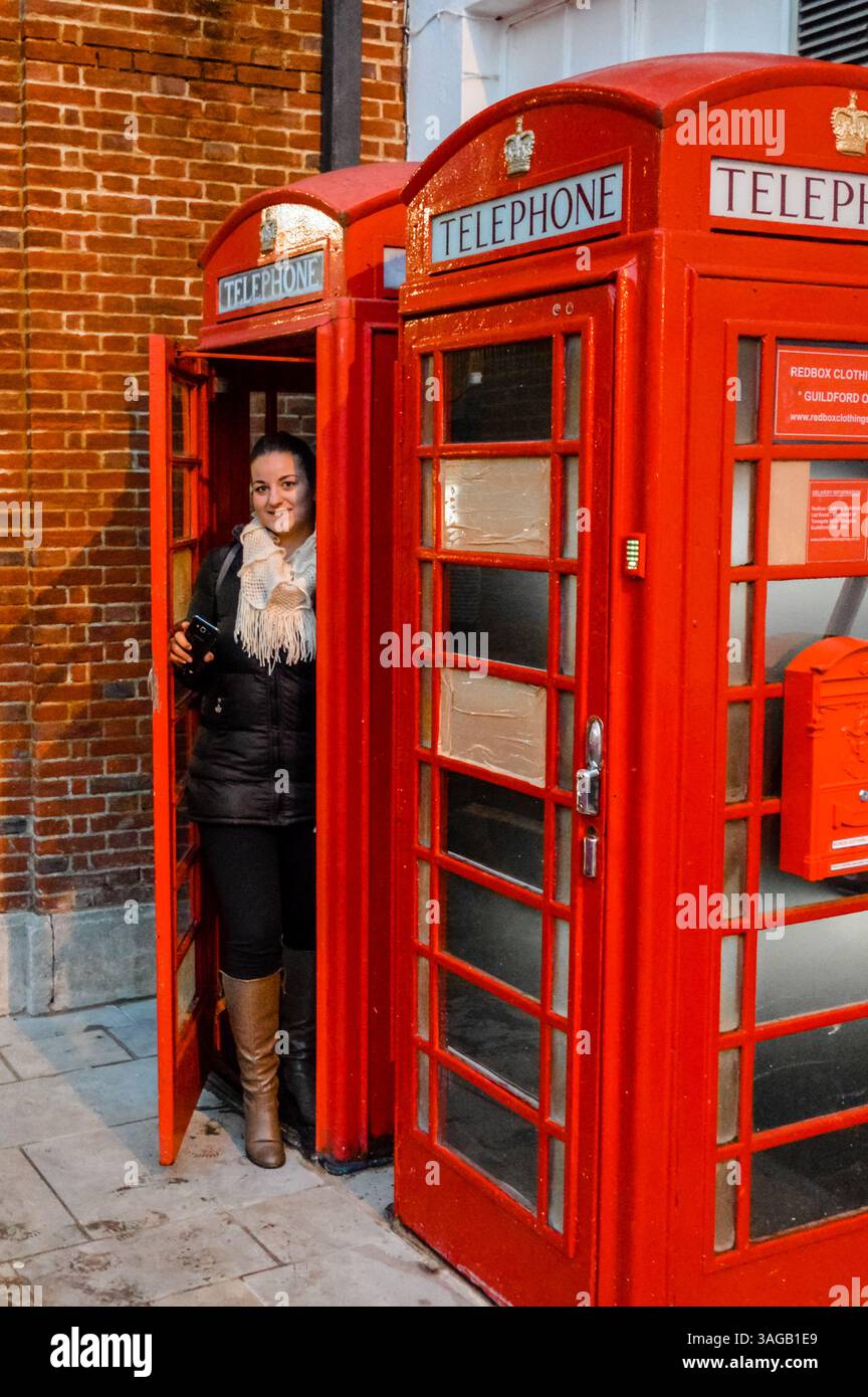 Portrait of a woman standing inside a traditional red telephone booth ...