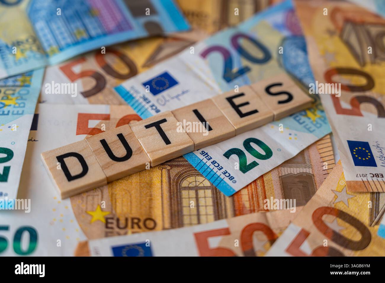 Word Duties, composed of wooden squares, over a field of banknotes ...
