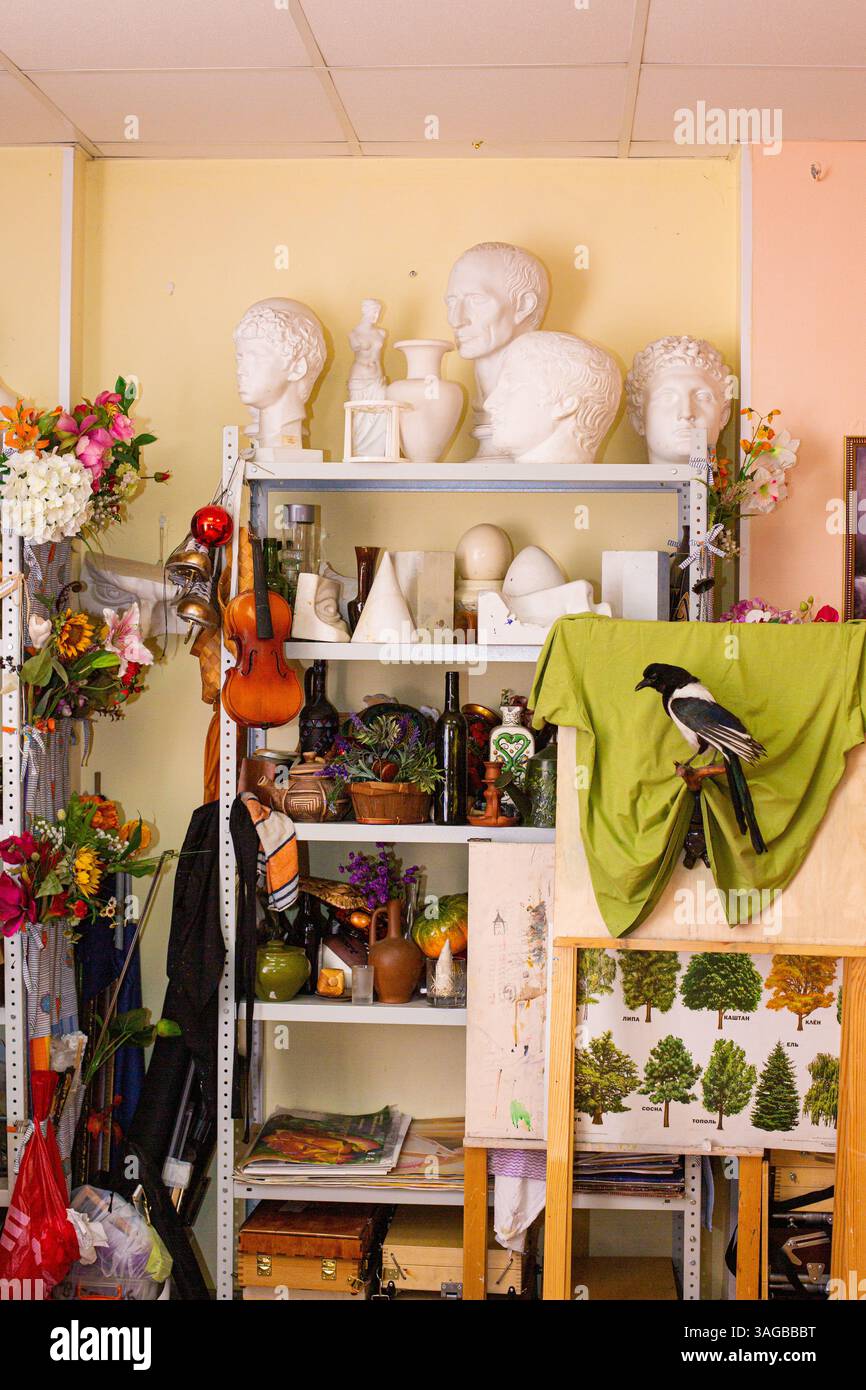 A cluttered room with a shelf full of white statues and a bird on a ...