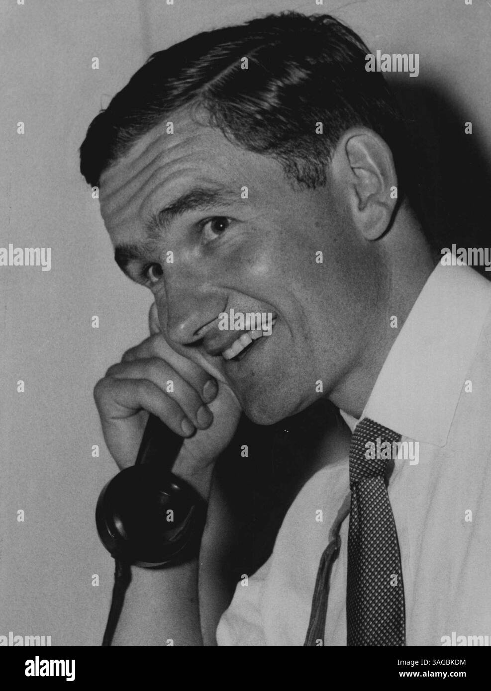 Jim Burke, at ***** in a city stockbroker office, smiles over the good ...