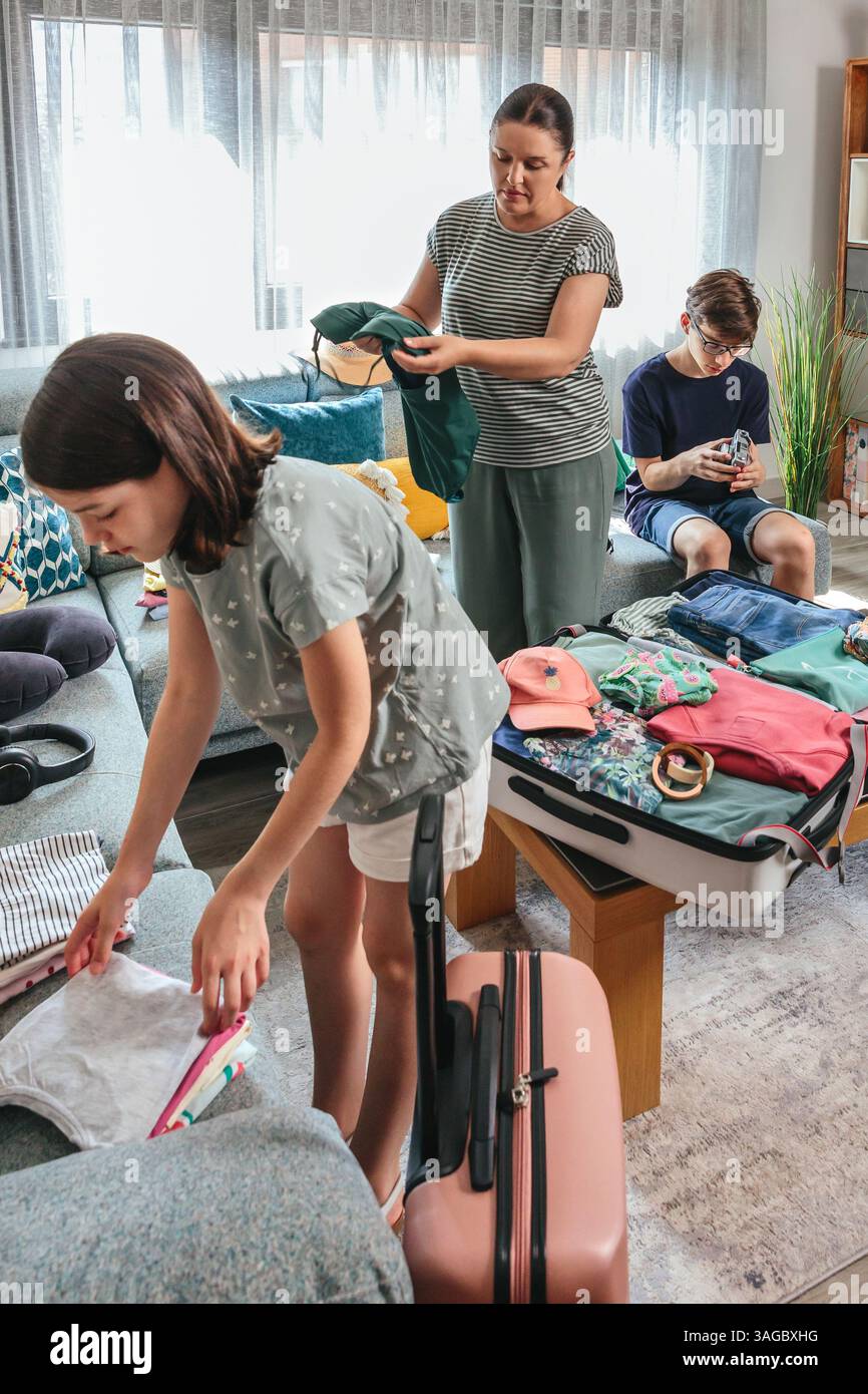 Family packing suitcases and bags for summer vacation in living room ...
