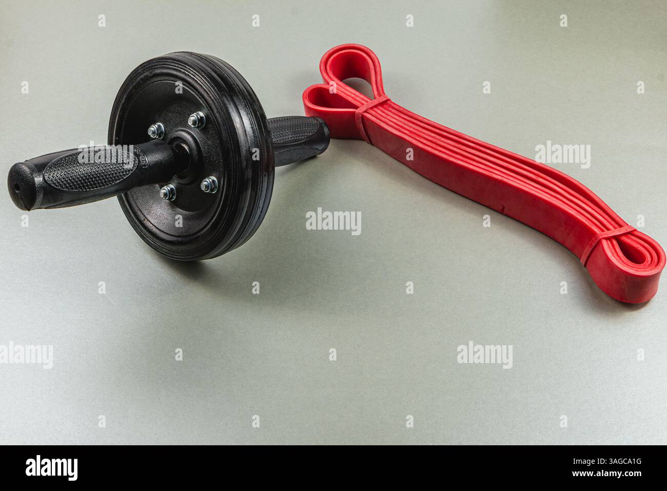 Fitness tools including a black ab roller and a red resistance band are ...
