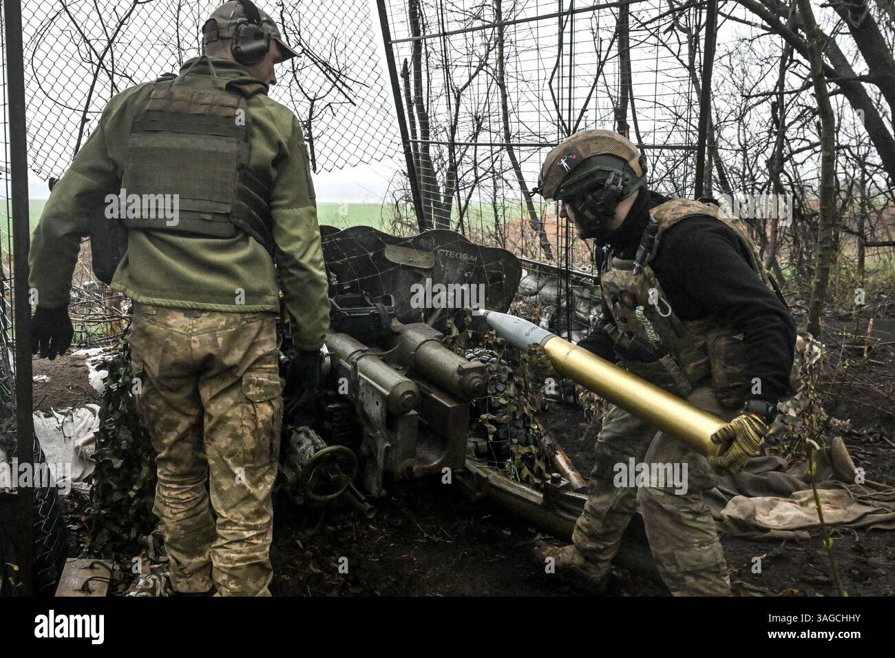 Servicemen of an artillery unit of the 108th Territorial Defence Brigade load a shell while on a ...