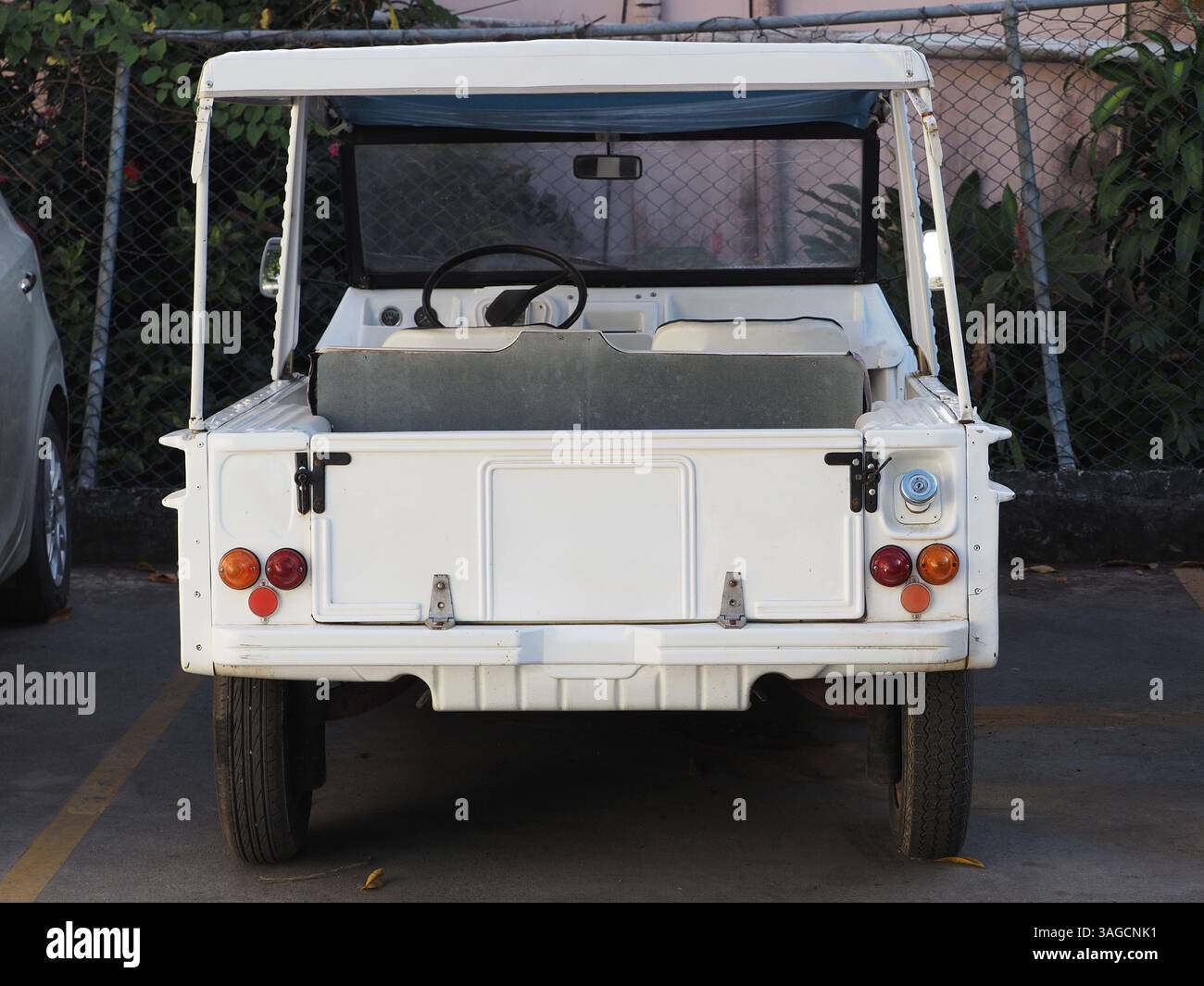 Compact white retro vehicle is parked outdoors. Vintage car. Back view ...