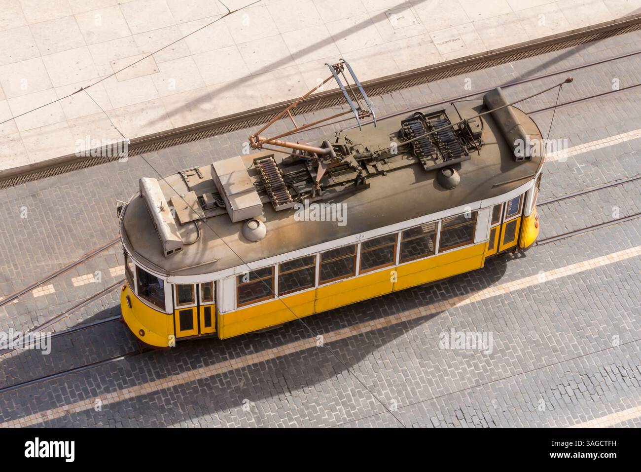 Historic yellow tram number 28 rides through a narrow street in Lisbon ...