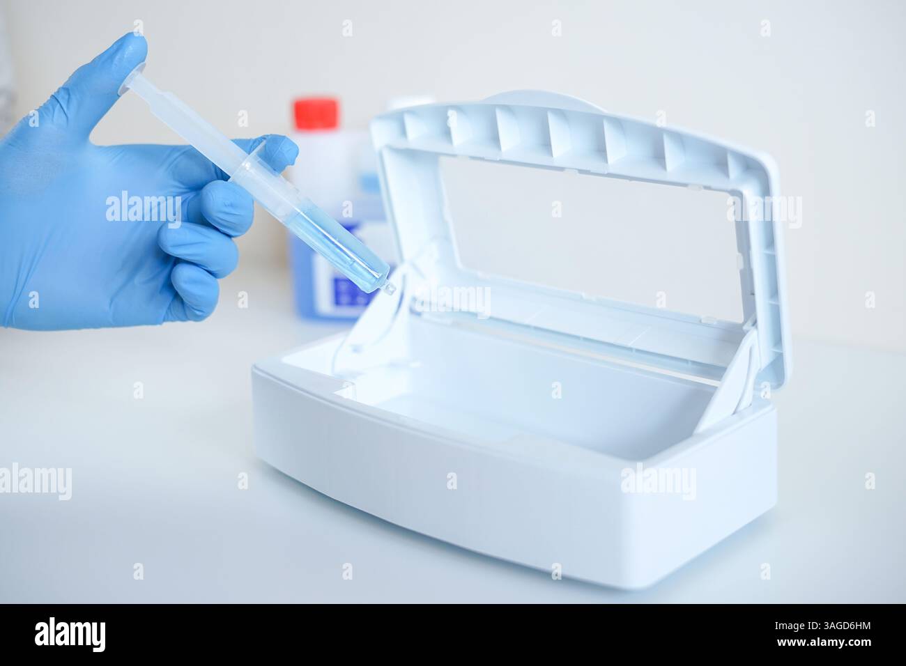A medical worker in gloves uses a syringe to add solution to a ...