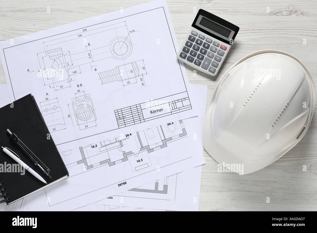 Different engineering drawings, hard hat, pen, divider and calculator ...