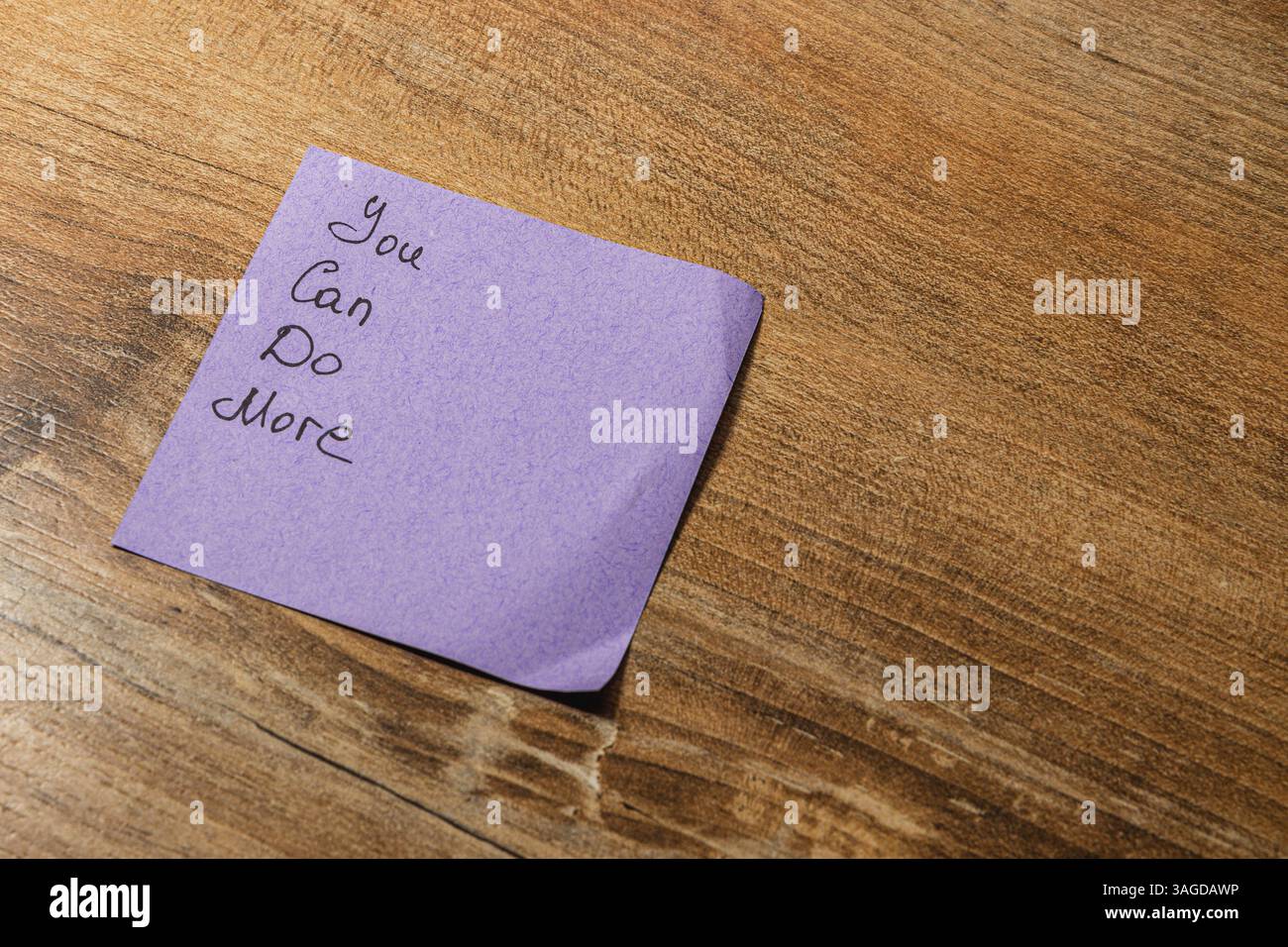 A purple sticky note with handwritten motivational words rests on a ...