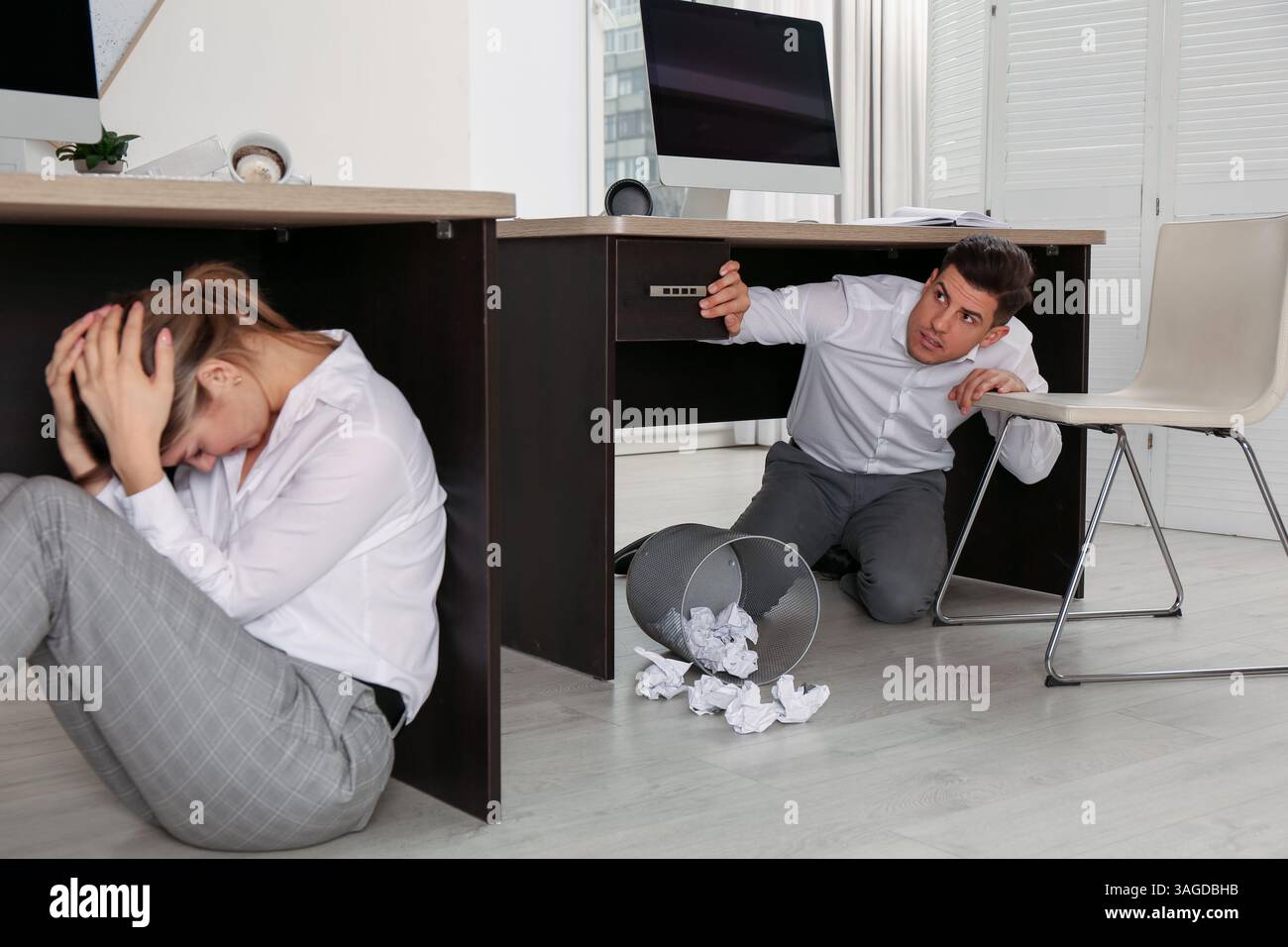 Scared employees hiding under office desks during earthquake Stock ...